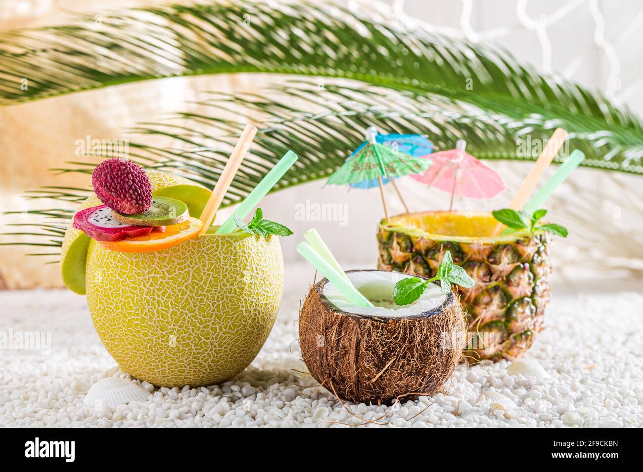 Cold drinks in tropical fruits on white pebbles. Drink for summer heat ...