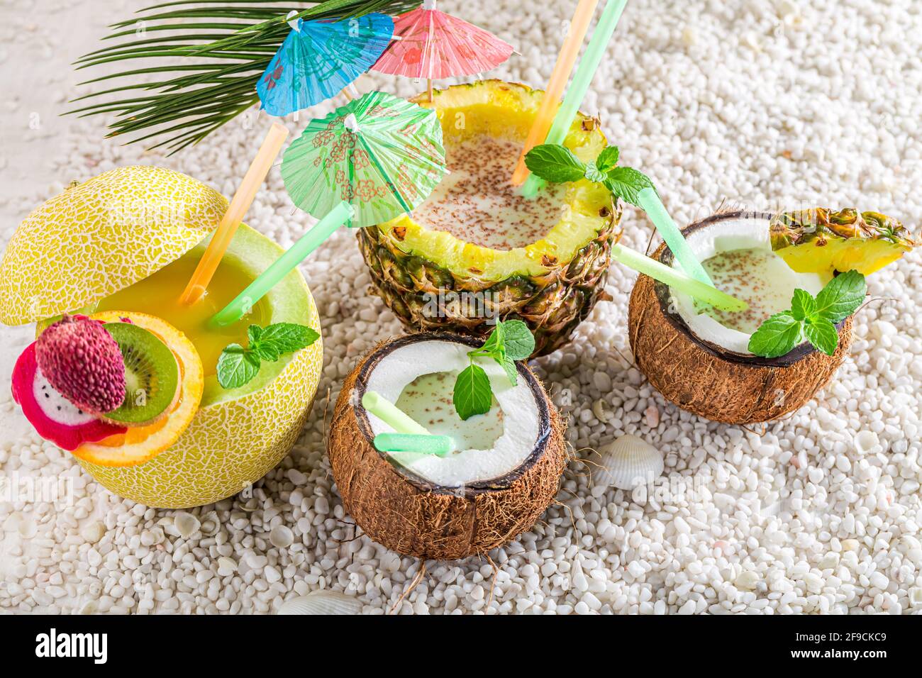 Sweet drinks in fresh tropical fruits on sandy beach. Drink for summer ...