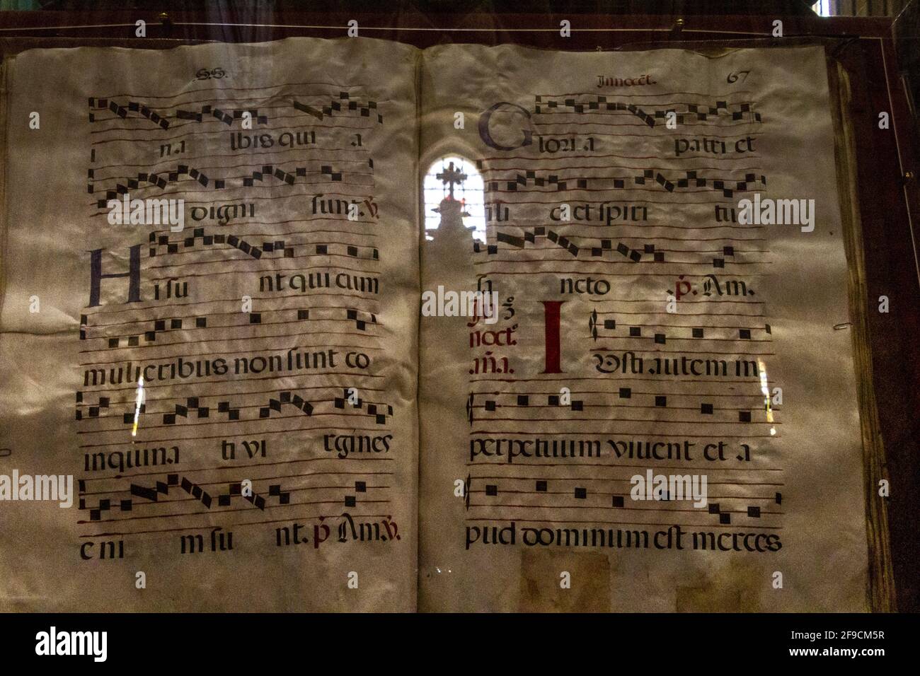 Closeup fragment of ancient manuscript with sunlight and cross from top ...