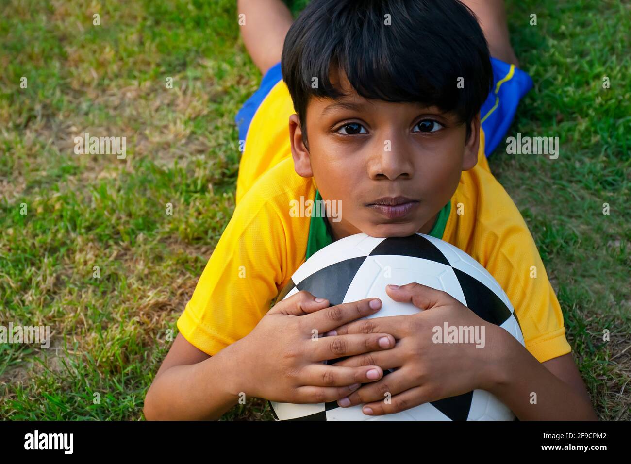 Young boy laying in the ground with football Stock Photo - Alamy