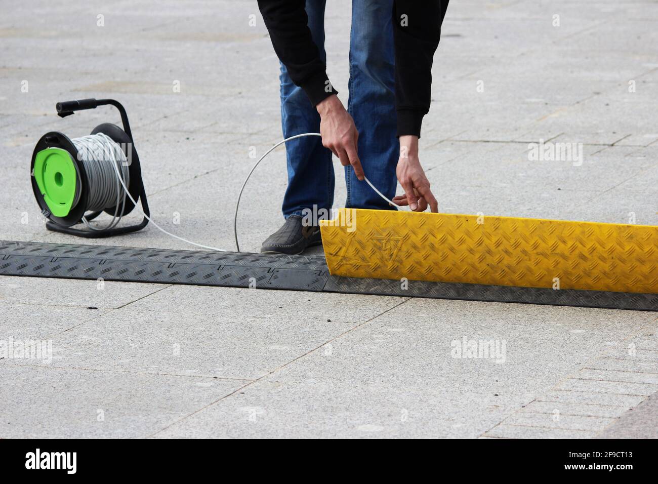 worker hides the wire in a ground multichannel plastic cable channel ...