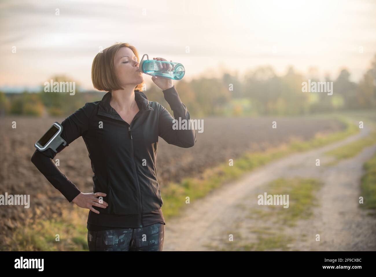 Young woman drinking while running Stock Photo - Alamy
