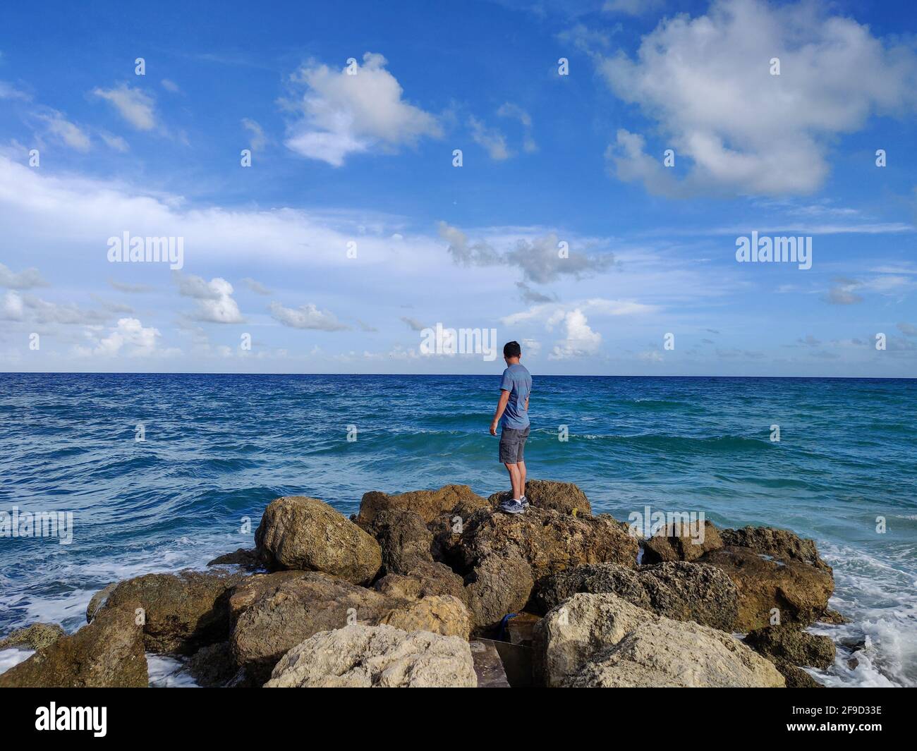 Back view of a male standing on rocks and facing the mesmerizing ...