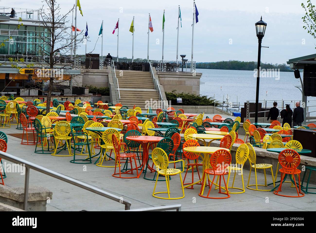 View of a cozy outdoor waterside cafe with colorful tables and chairs ...
