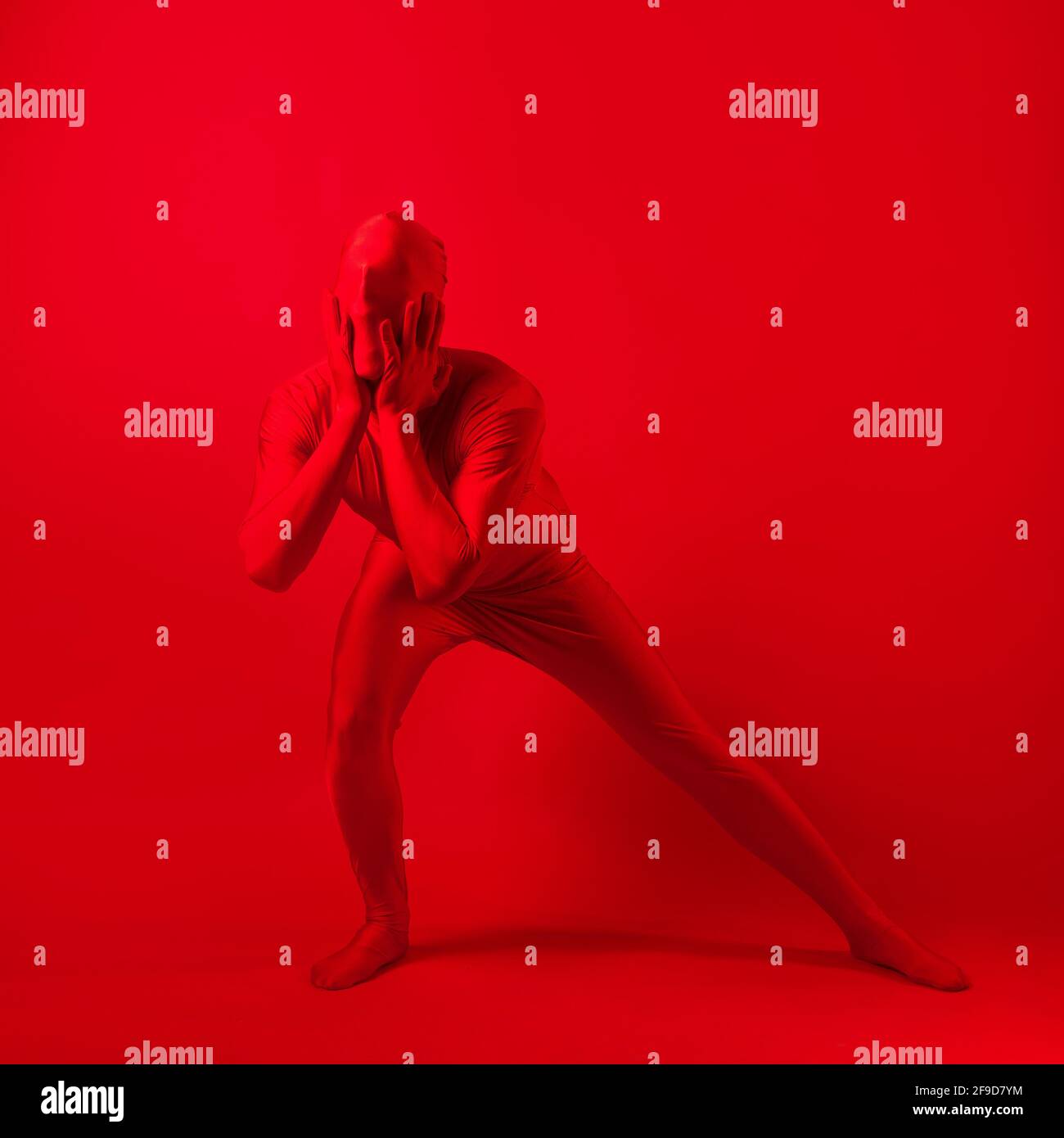 A screaming man in a red full suit, on a red background. The concept of ...
