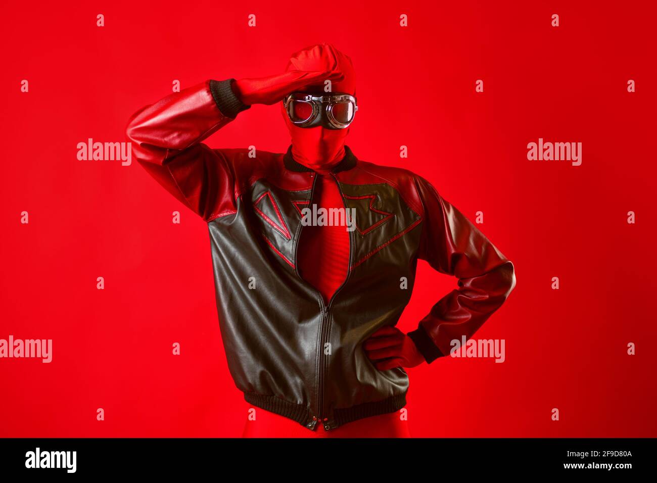 A funny super hero in a red leotard and protective glasses hands on the ...