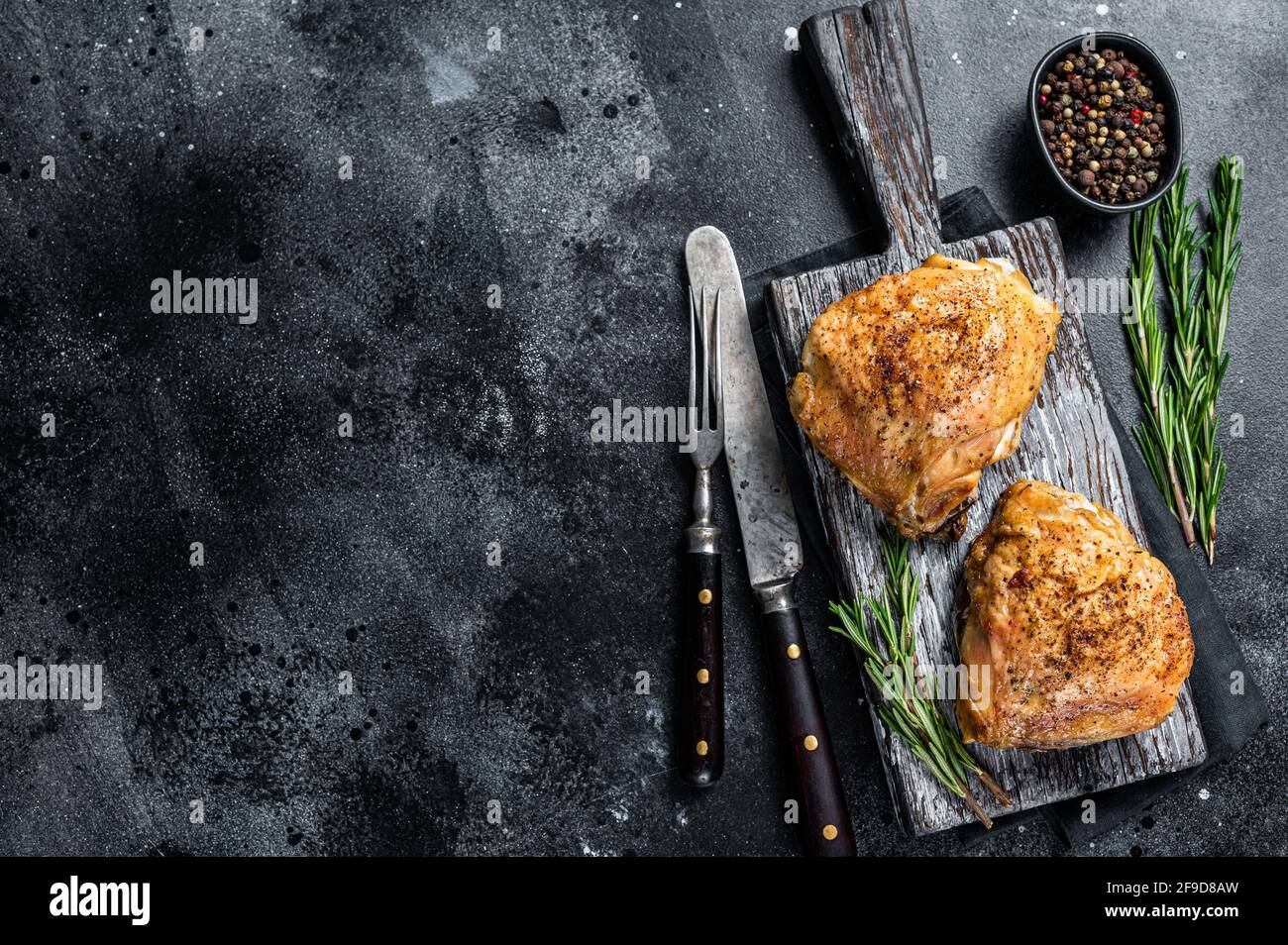 Spicy Bbq grilled chicken thighs on a wooden board with rosemary. Black ...