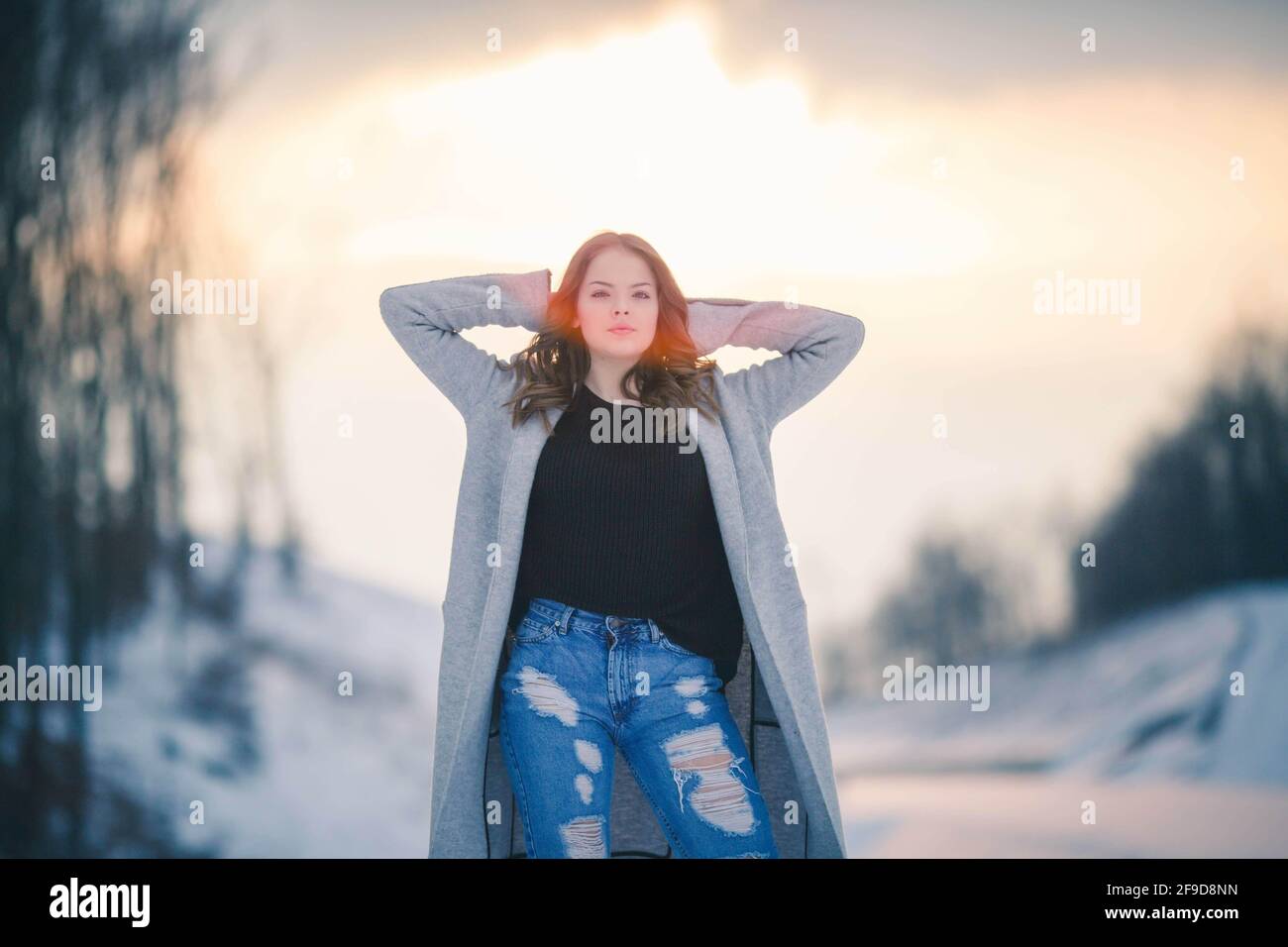 Shallow focus of a Bosnian Caucasian woman holding her hair against a winter forest background ...