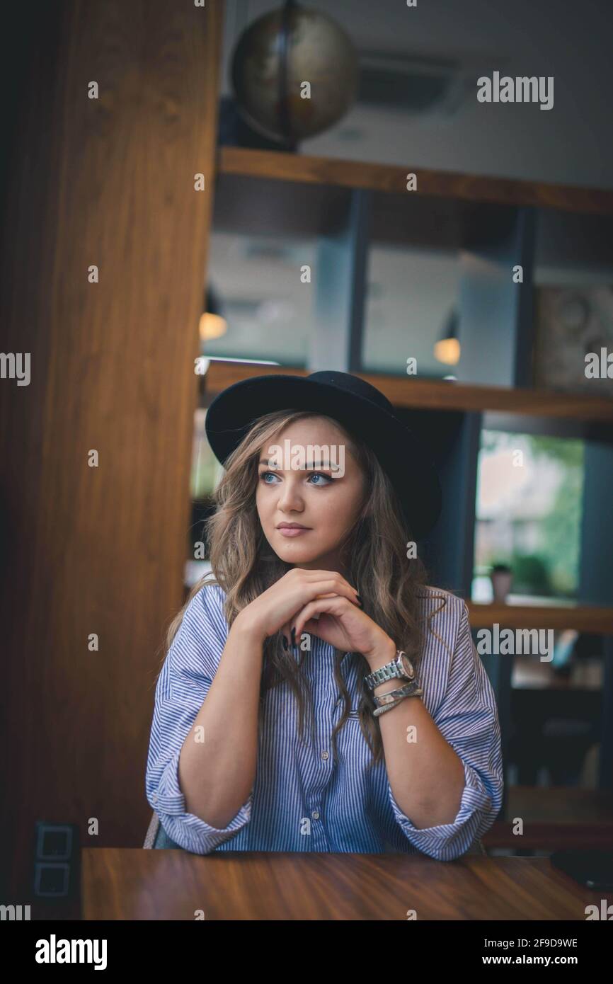 Vertical shot of a beautiful Bosnian Caucasian woman in a hat posing in ...