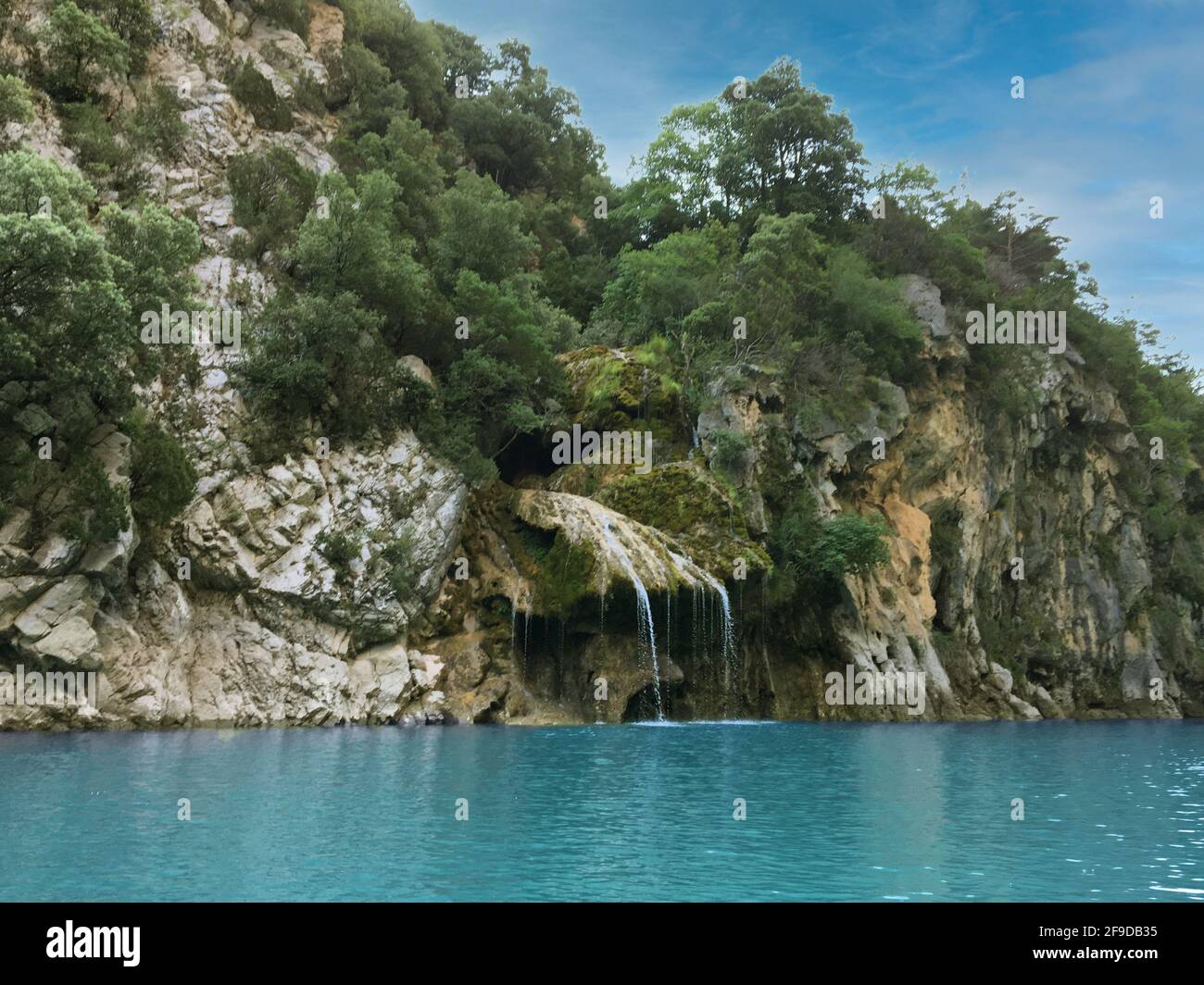 Small waterfall and a lake surrounded by rocky cliffs covered in ...