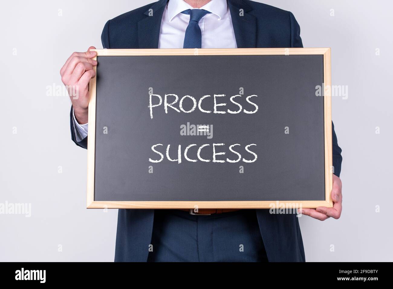 Businessman wearing a suit and holding a blackboard with "Process ...