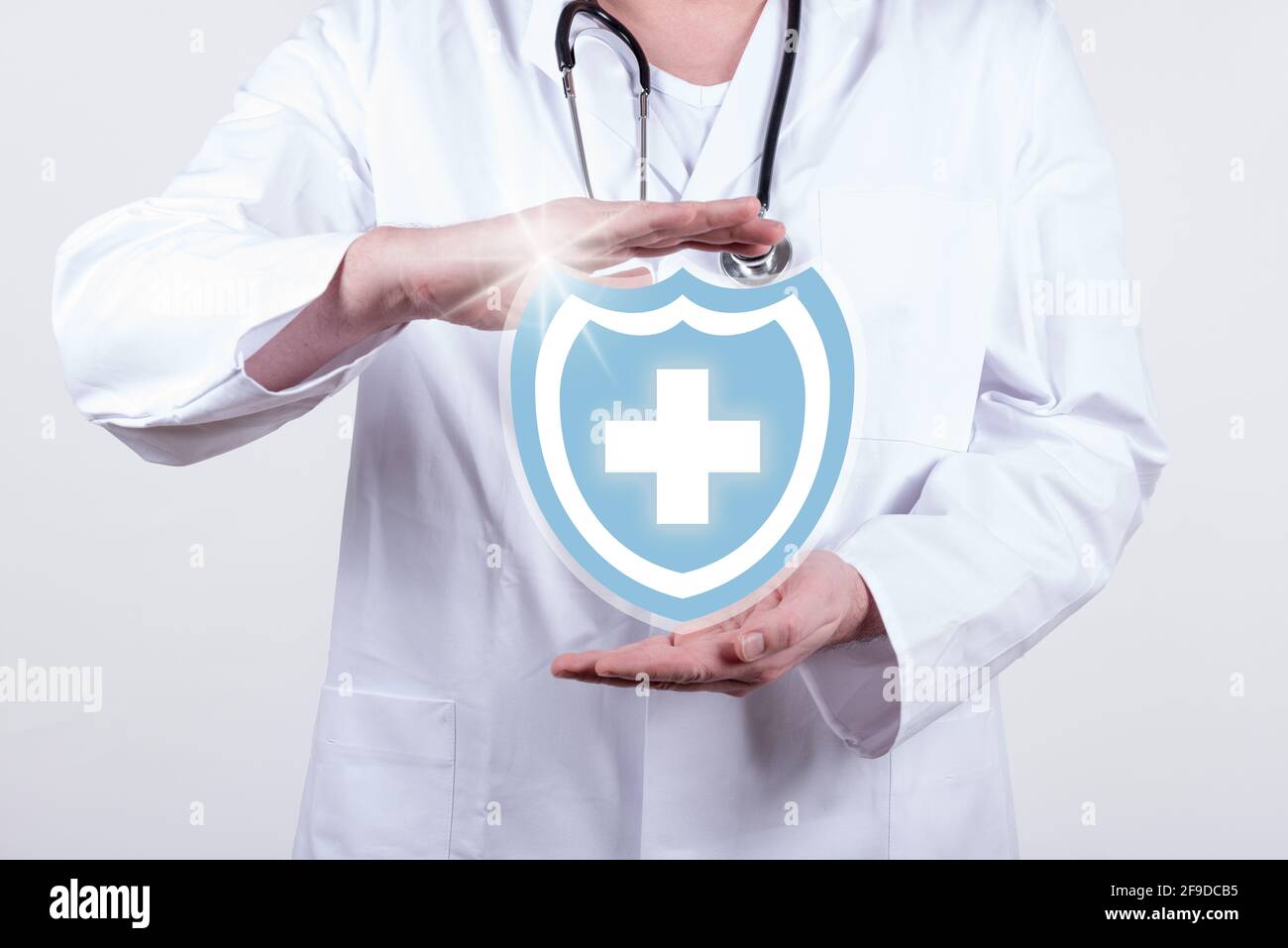 Unrecognizable doctor holding the sign of the medical cross on a white ...
