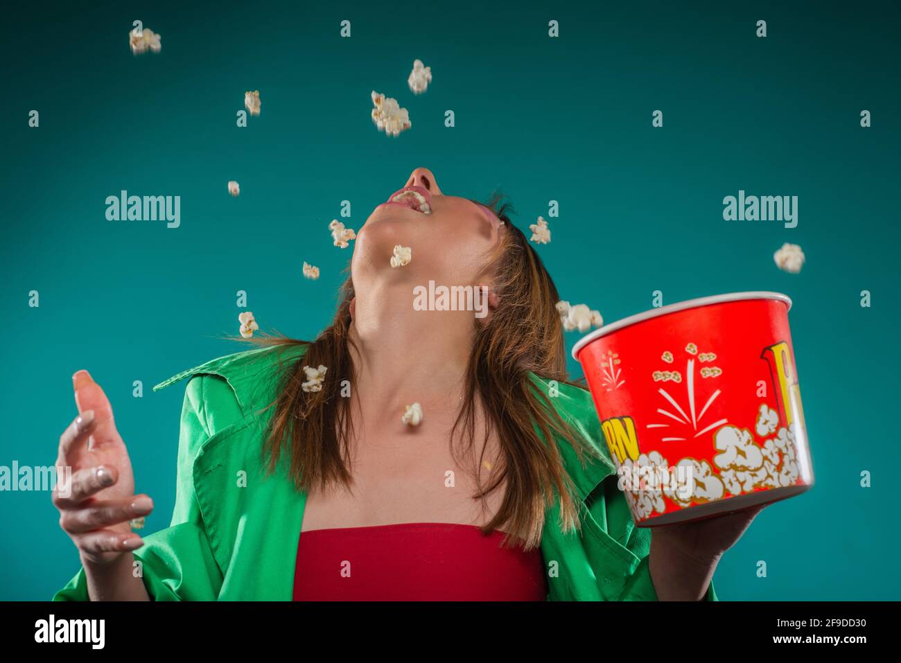 Beautiful girl is throwing and catching the popcorn with her mouth ...