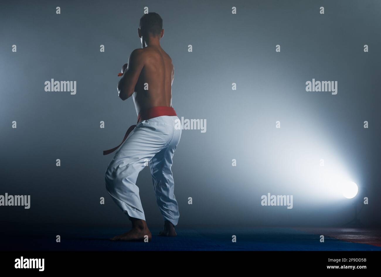 Male karate fighter performing kick isolated on dark background in the ...