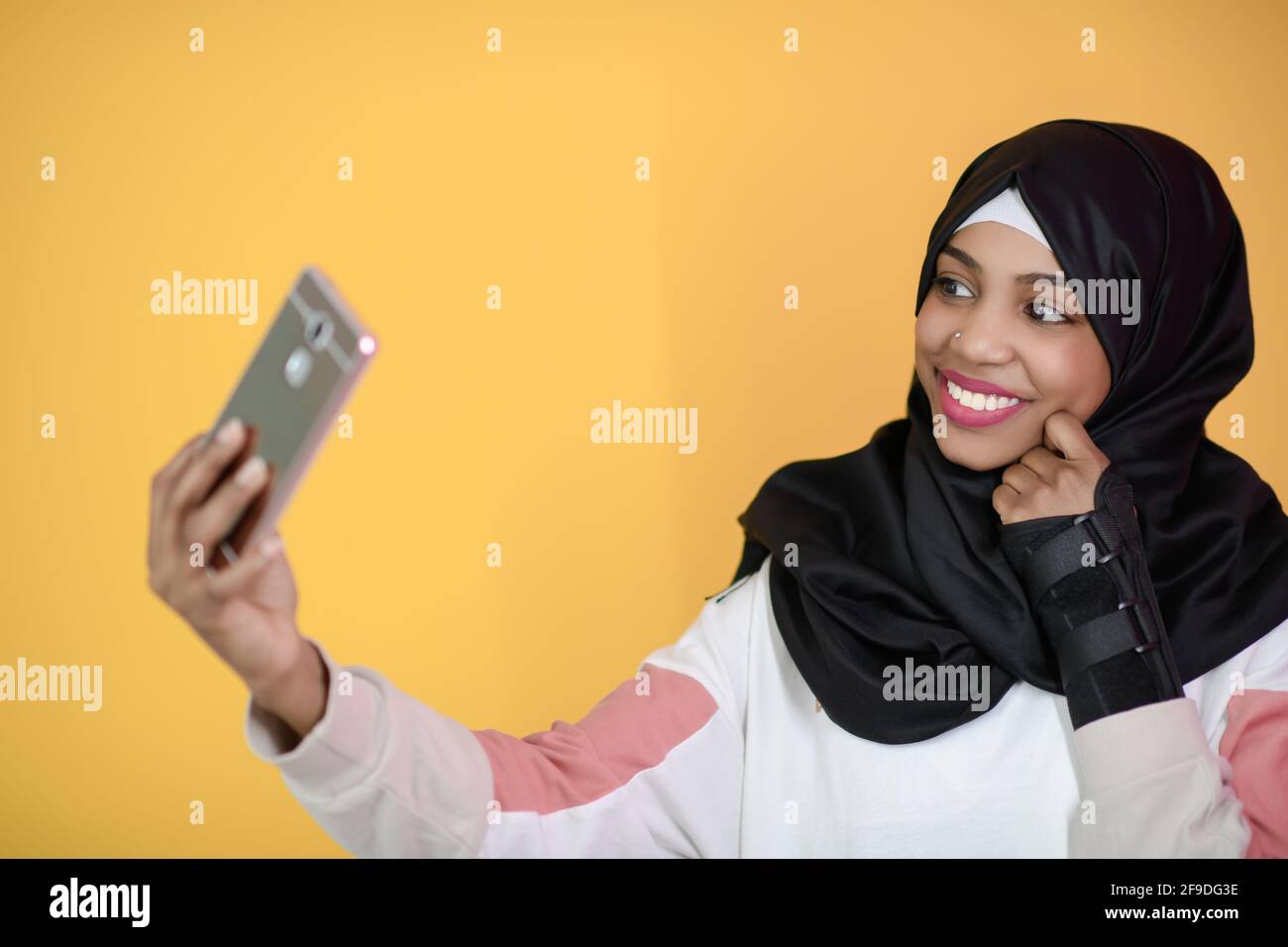 african muslim woman with a beautiful smile takes a selfie with a cell ...