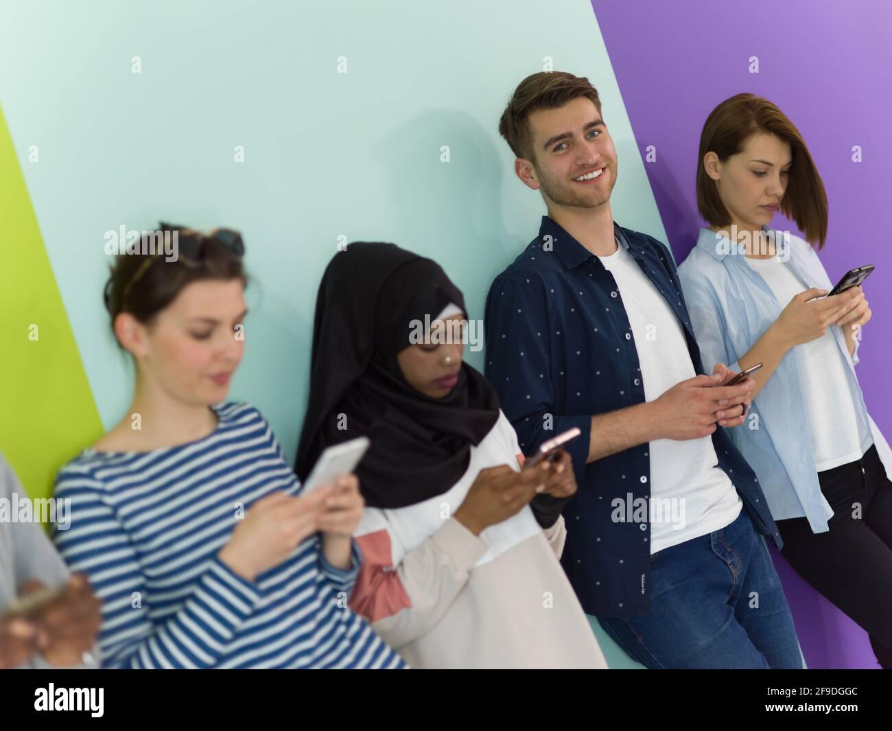 diverse teenagers use mobile devices while posing for a studio photo in ...