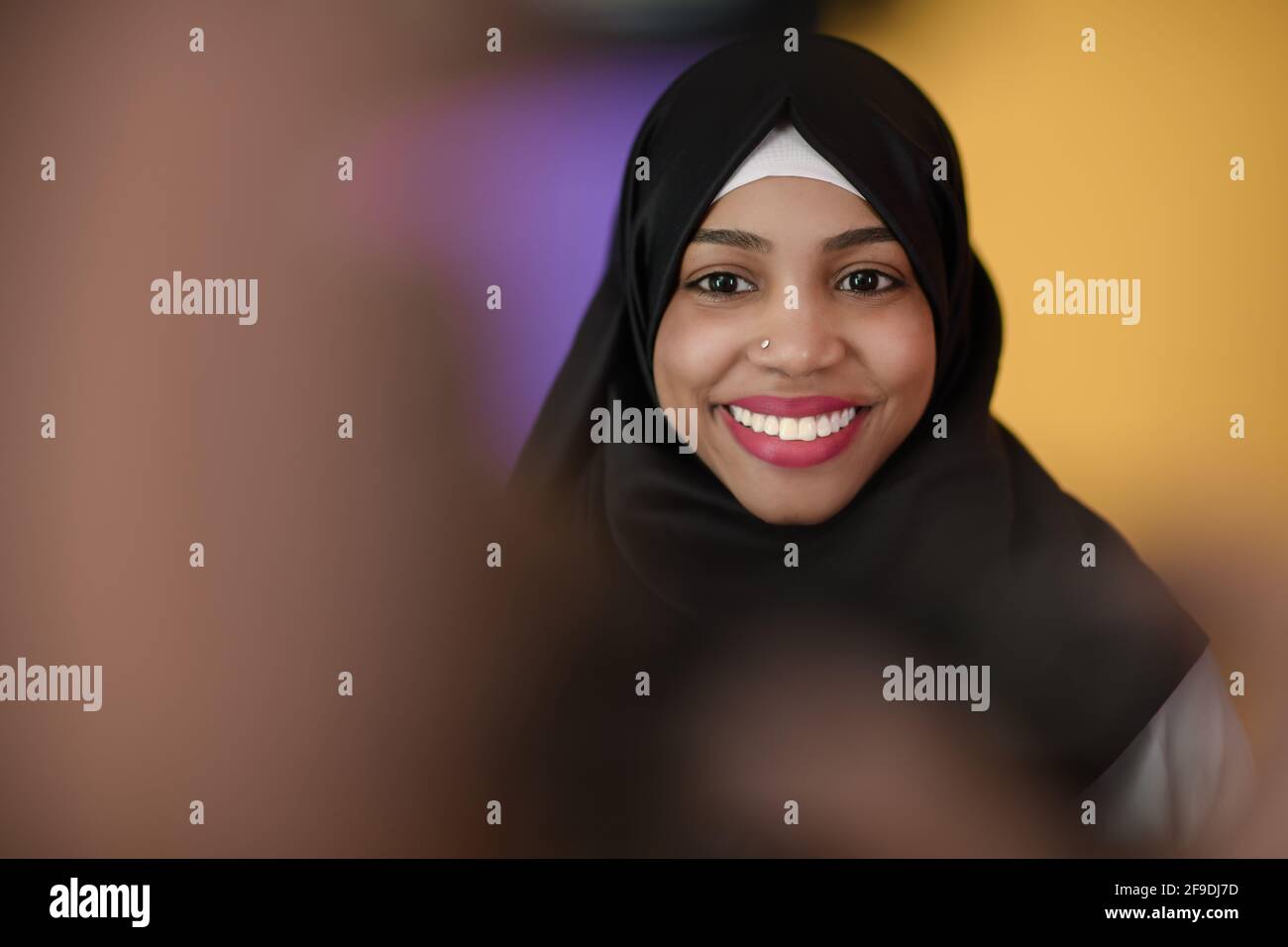 muslim woman with a beautiful smile wearing a hijab poses in the studio ...