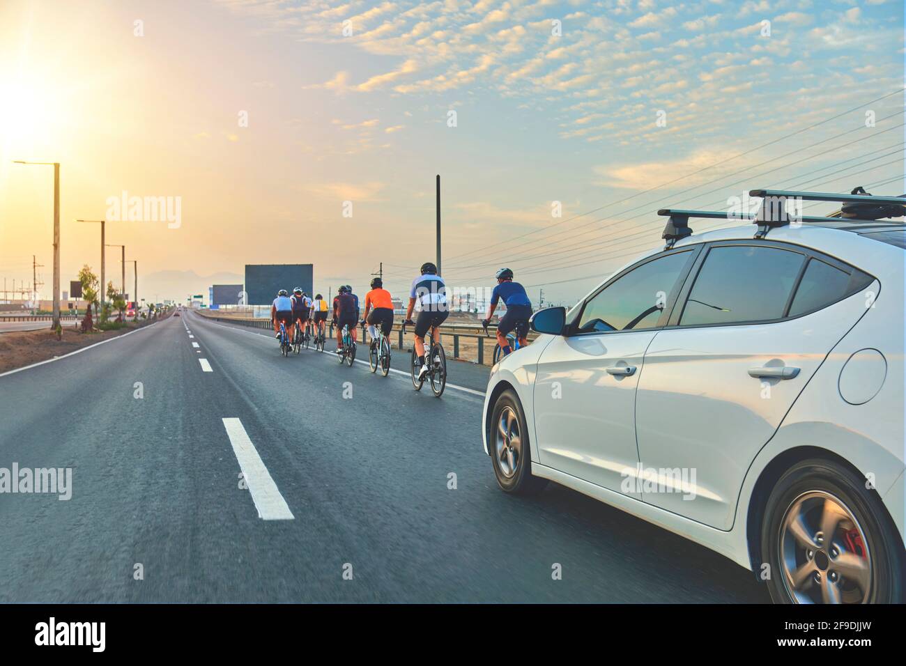 Group of professional cyclists training on highway with safety escort ...