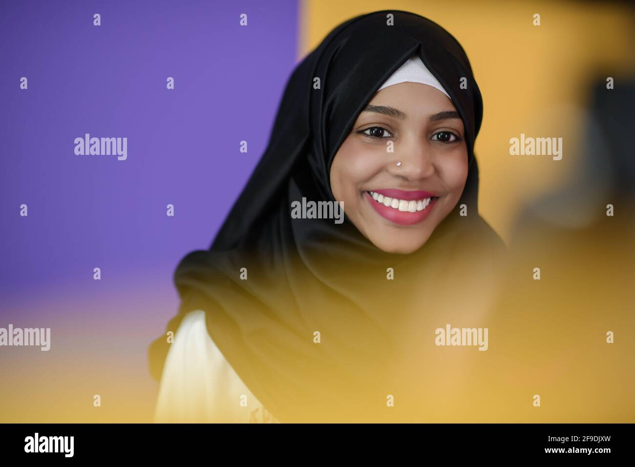 muslim woman with a beautiful smile wearing a hijab poses in the studio ...
