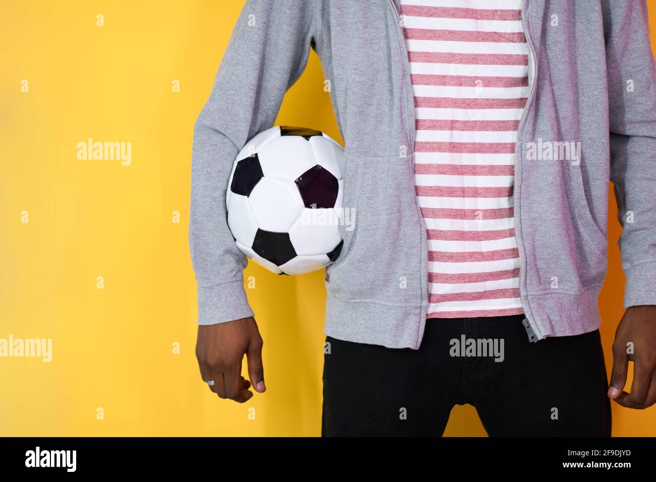 afro man posing on a yellow background while holding a soccer ball ...
