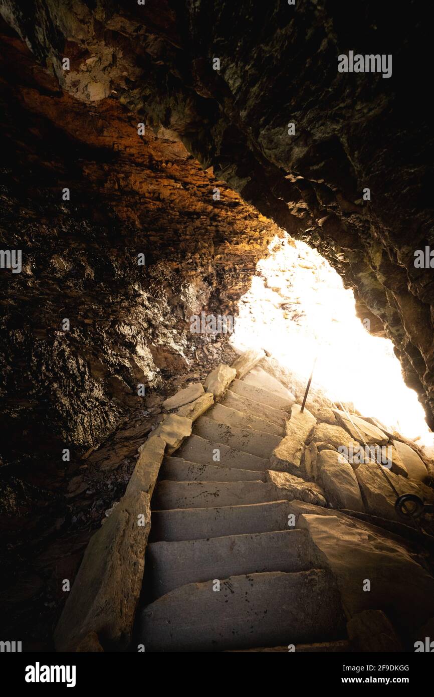 trail stairs down through a cave archway into the sun Stock Photo - Alamy