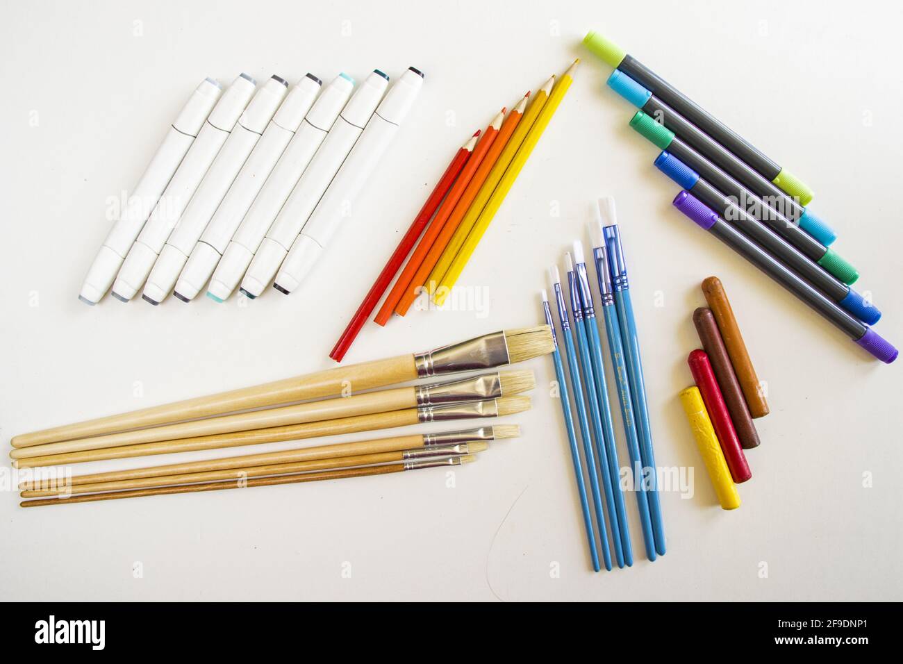 A top view of paintbrushes and crayons with colorful markers and ...
