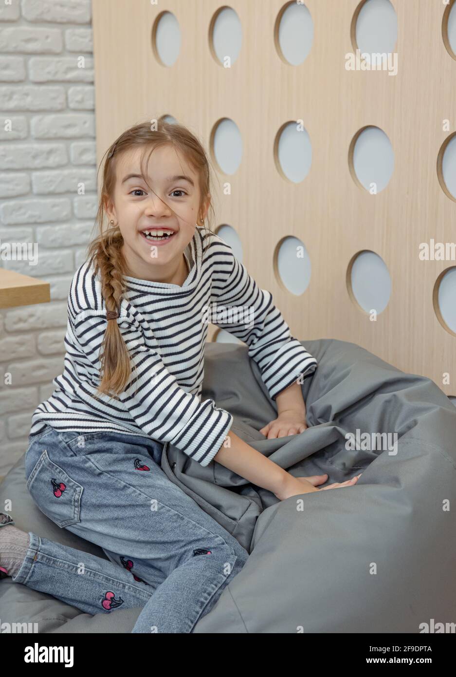 Cheerful little girl is resting in a comfortable beanbag chair Stock ...