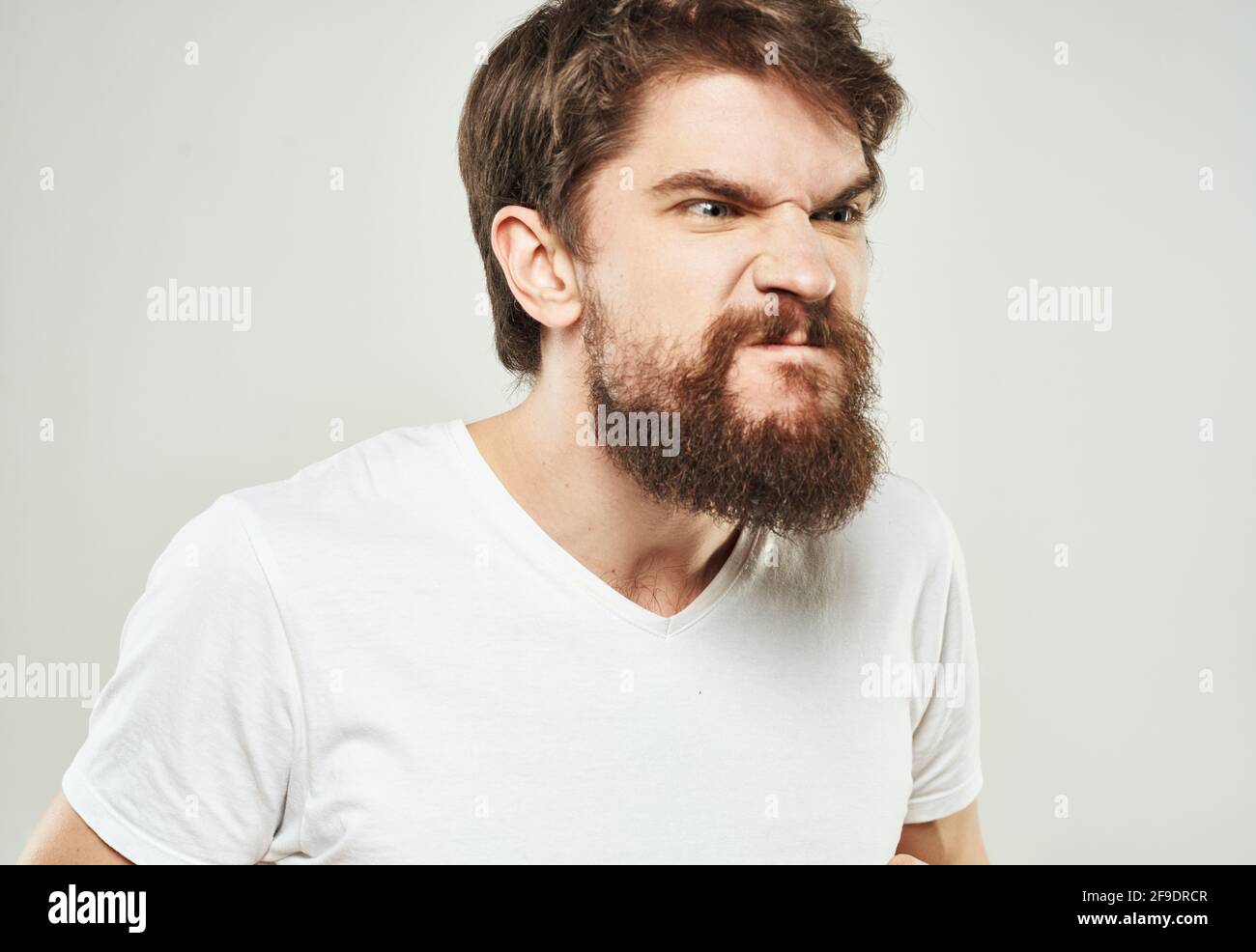 Aggressive man yells against a light background and gestures with his ...