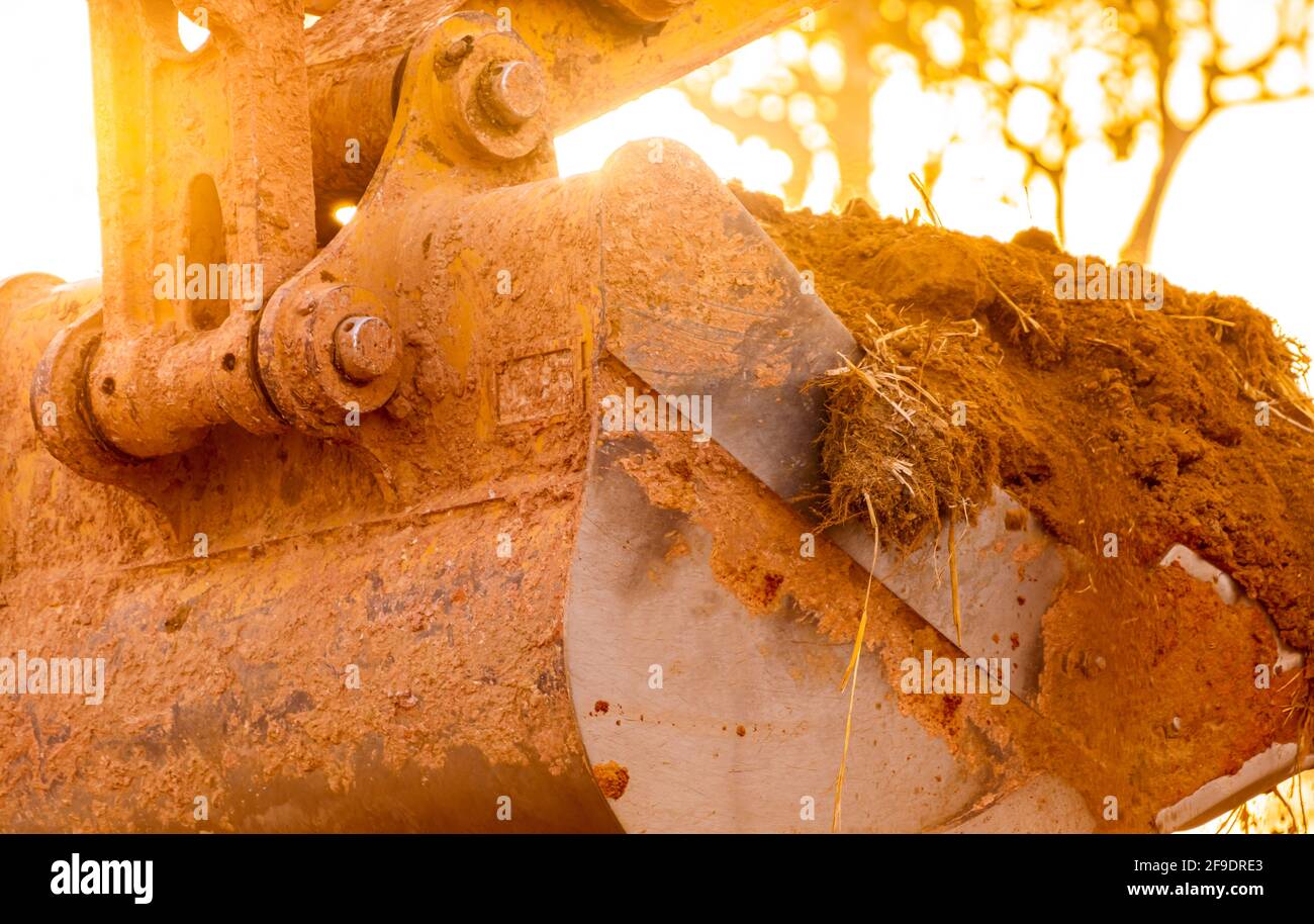 Backhoe working by digging soil at construction site. Bucket of backhoe ...