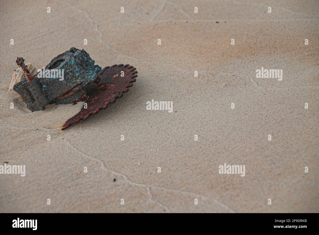 A closeup shot of an old rusty piece of metal thrown on the sand on a ...