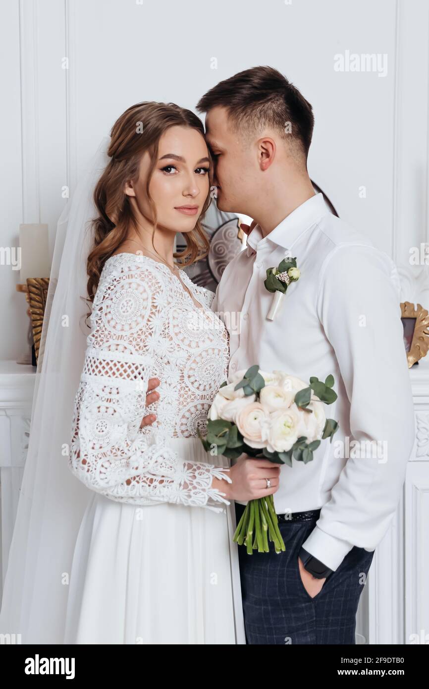 The groom hugs the bride in a boho style lace wedding dress in a cozy ...