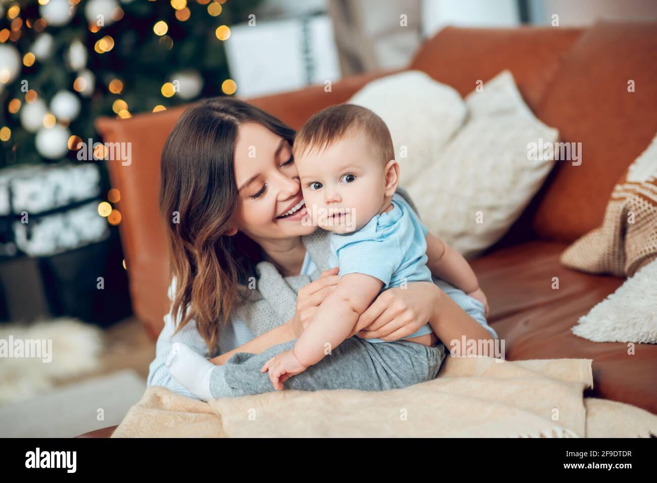 Happy mother with drooping eyelids touching baby Stock Photo - Alamy
