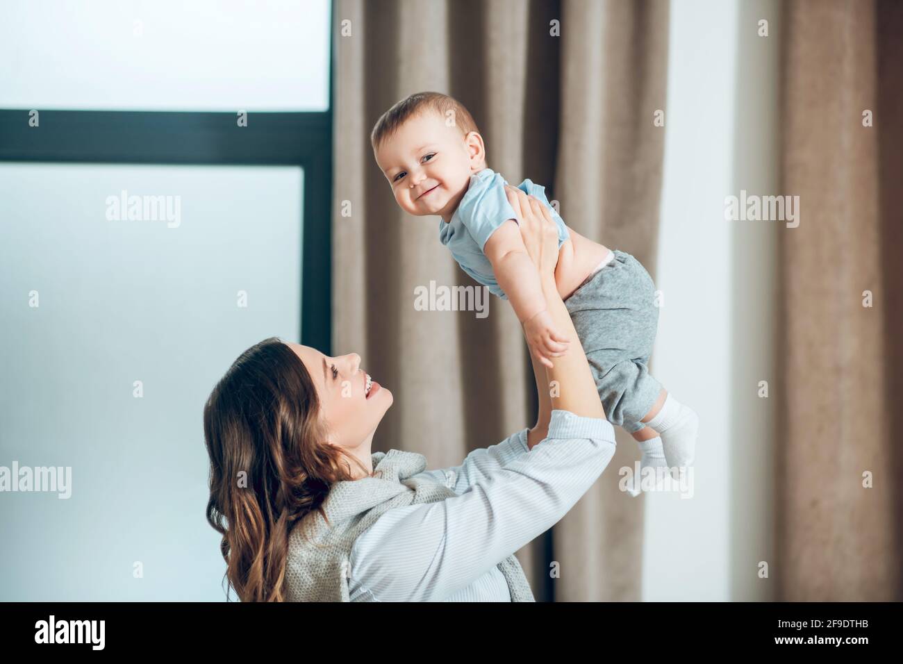 Happy mom raising up happy little child Stock Photo - Alamy