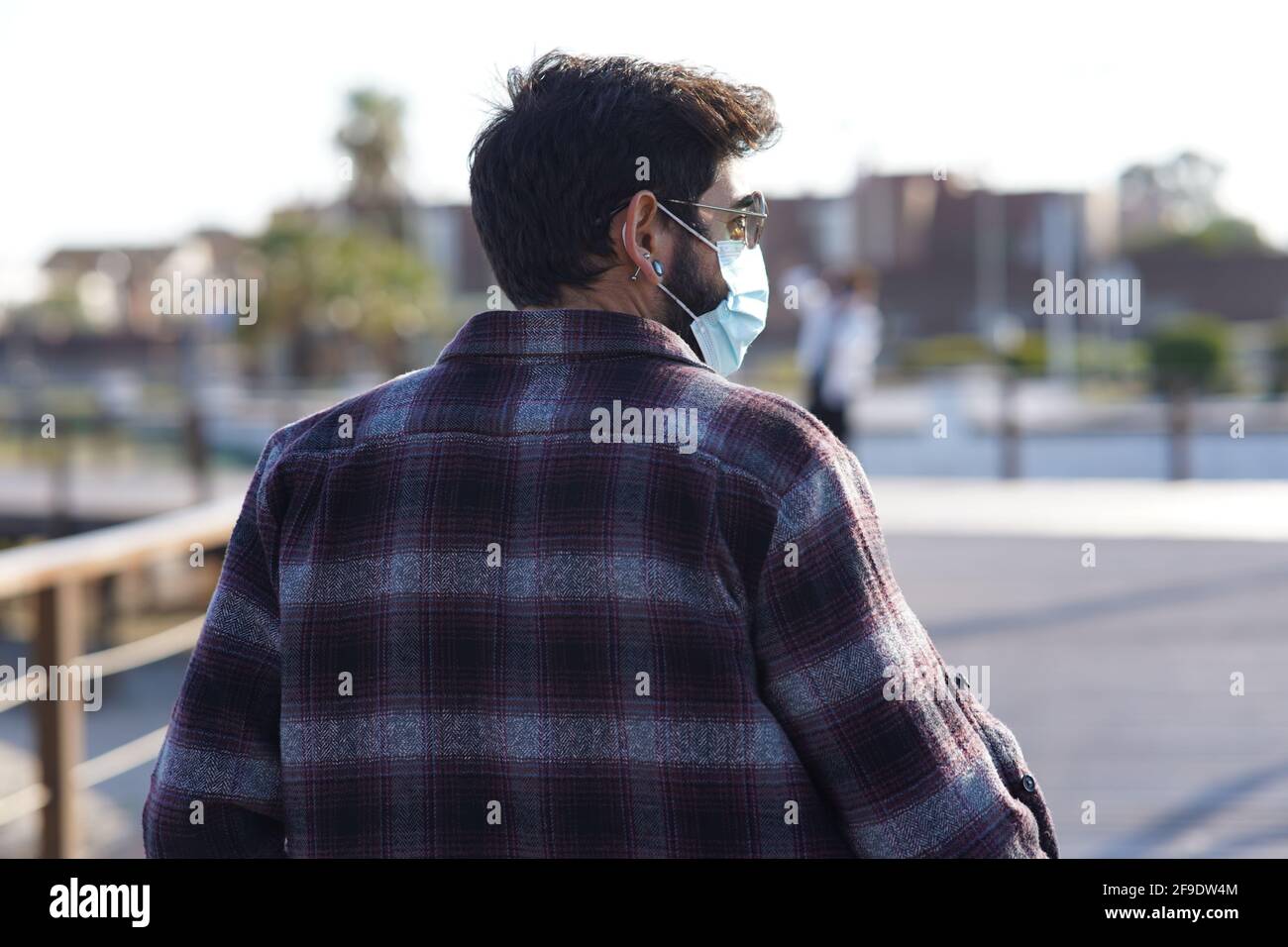 A shallow focus of a young Spanish guy wearing a checkered shirt and a ...