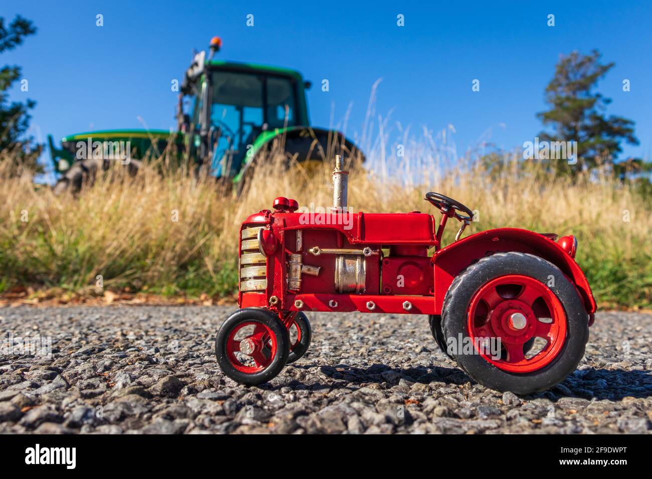 One small model tin model tractor, with a big green tractor in the ...