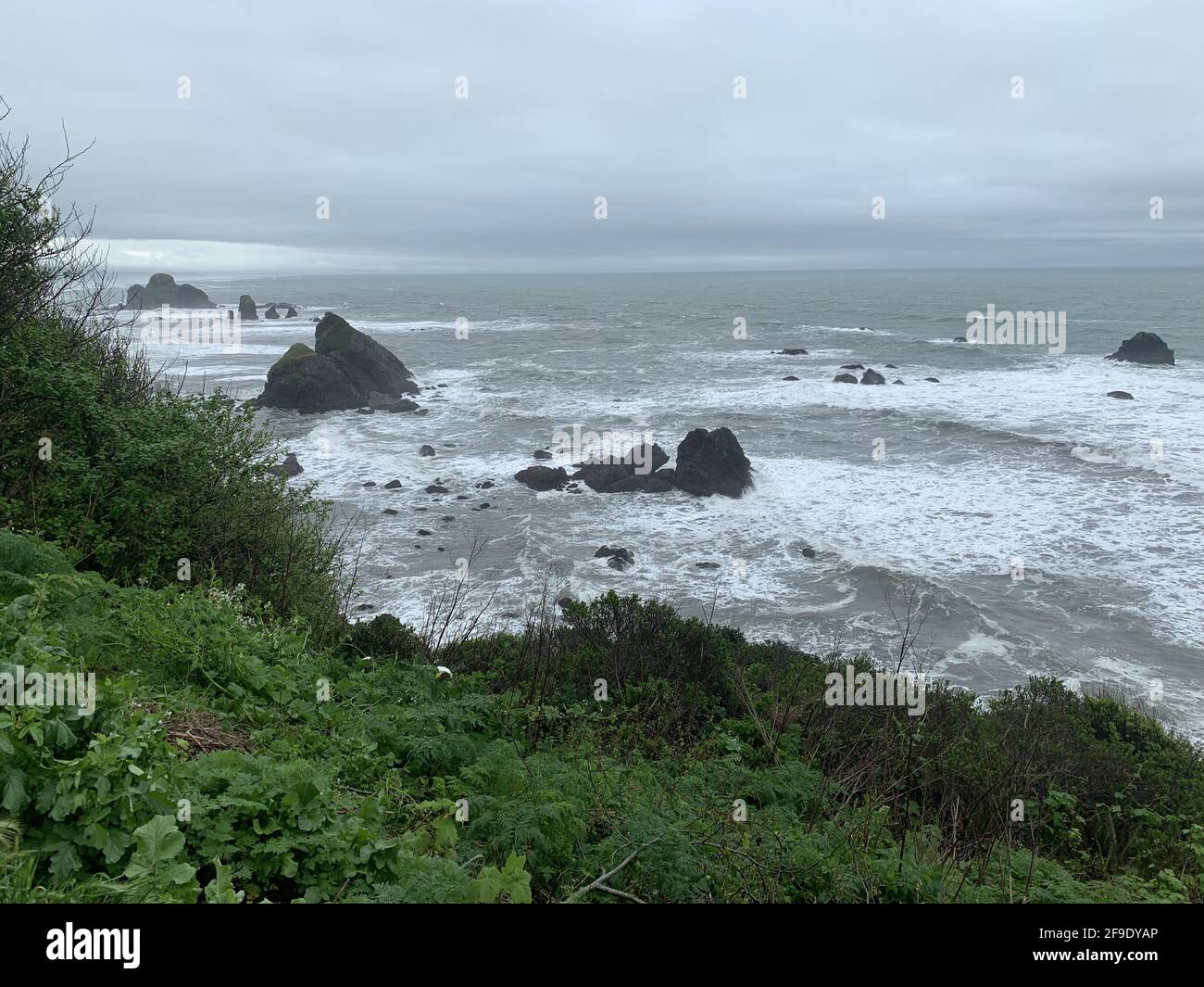 A scenic coastline view of rocks emerging from the water in a cove of ...