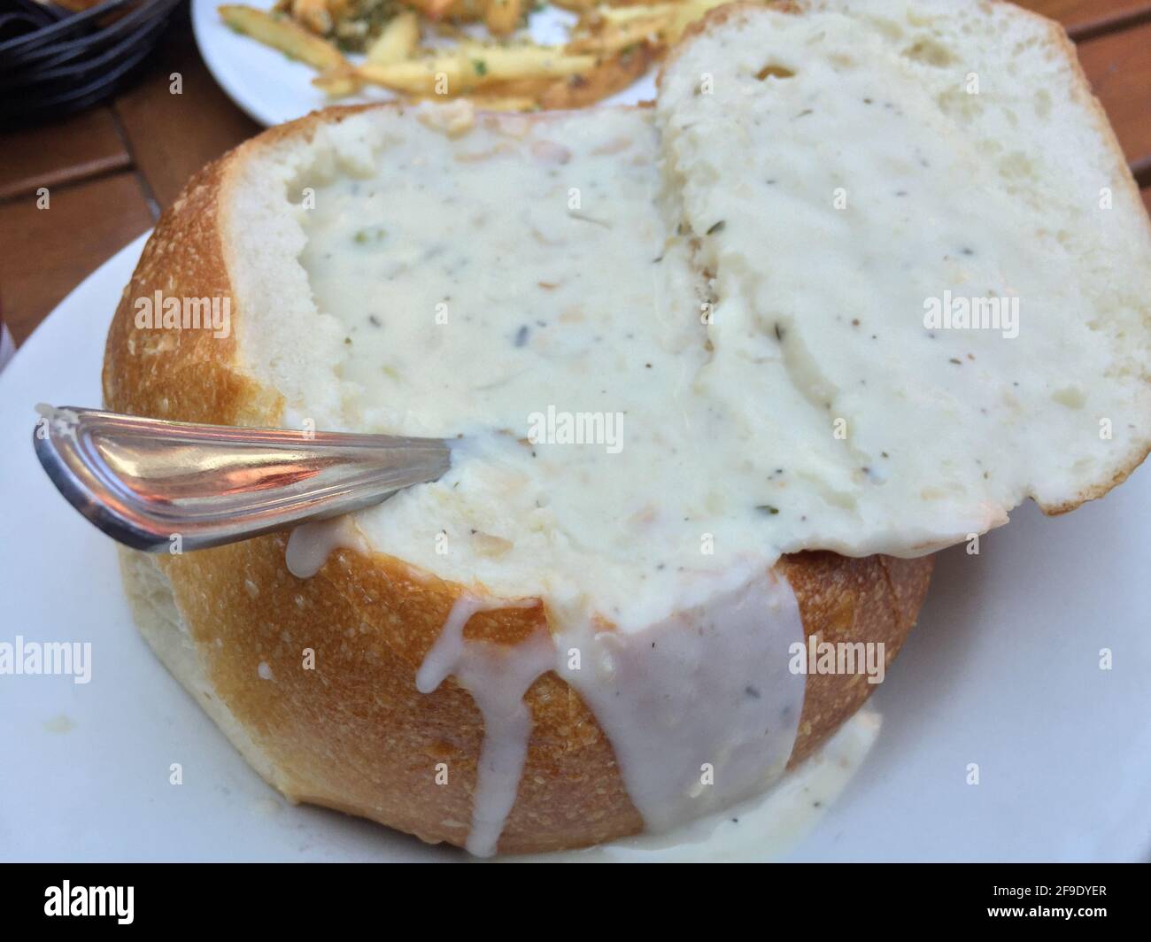 A closeup of white clam chowder inside a sourdough bread bowl in ...