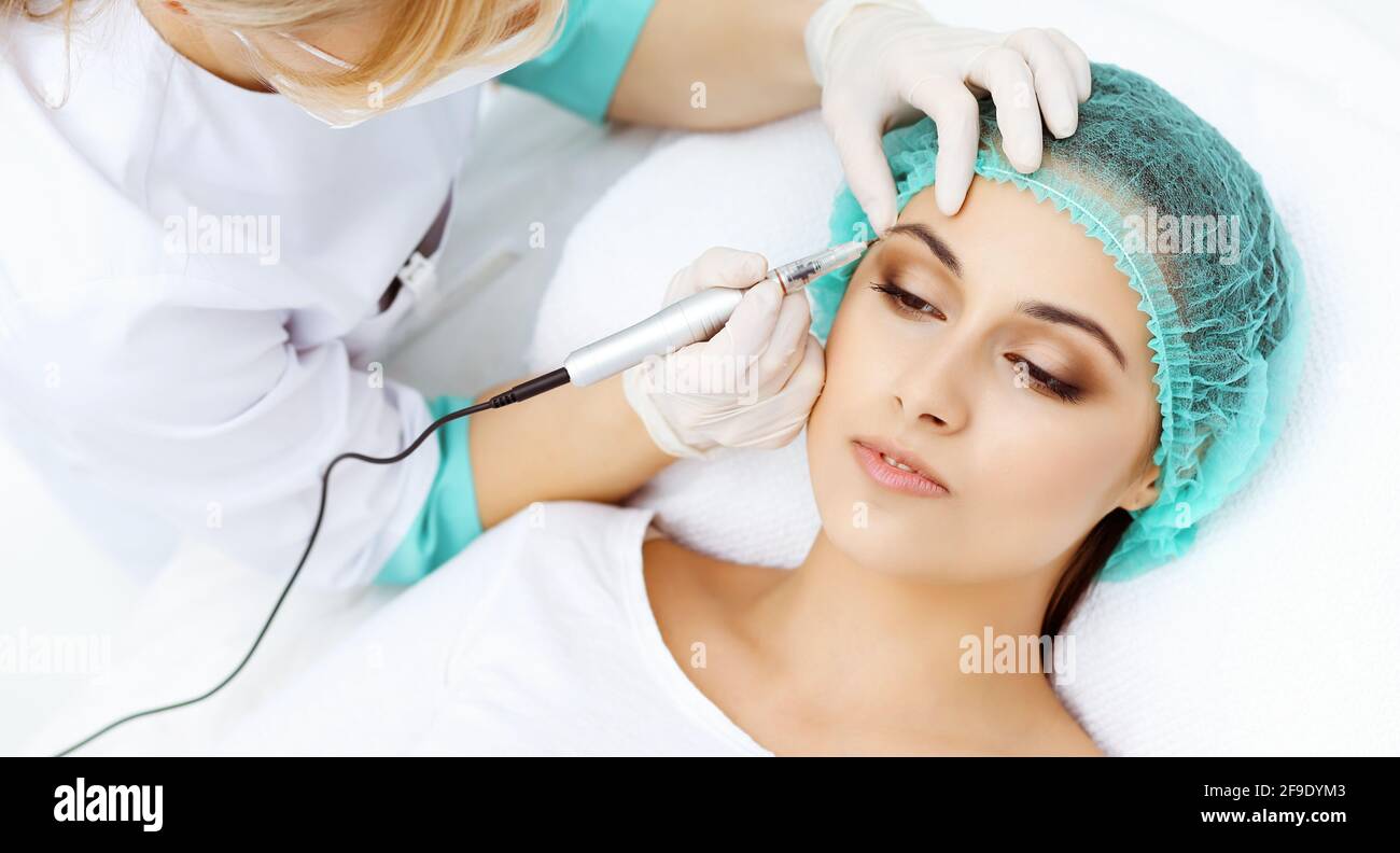 Professional beautician doing eyebrow tattoo at woman face. Permanent ...