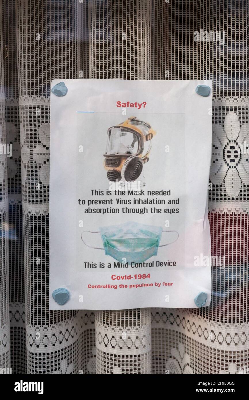 Anti face mask sign in a front window with a lace curtain behind it ...