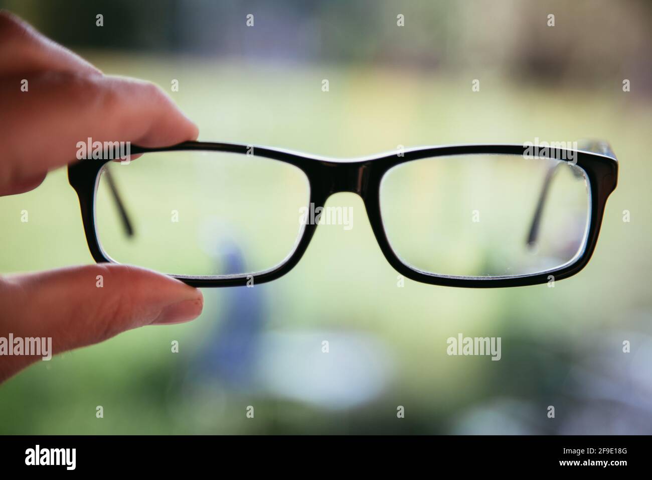 Young man holding his glasses outdoors, blurry background Stock Photo ...