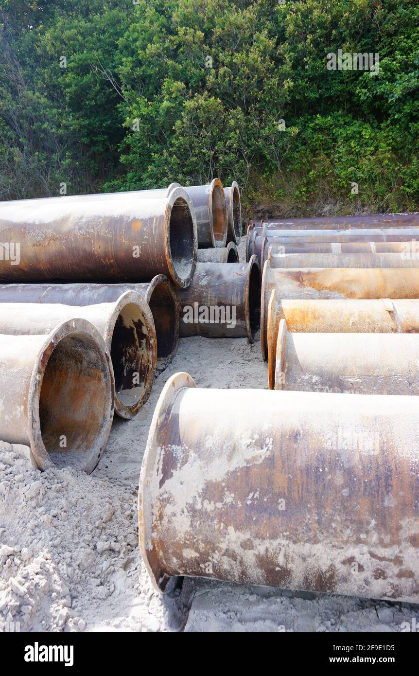 A vertical shot of rows of metal pipes on a sandy beach in Sianozety ...