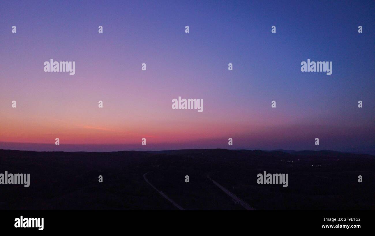 The beautiful scenery of road on a meadow with pink sunset background ...