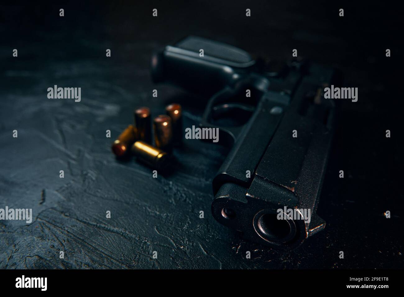 Black gun and bullets on concrete table. Firearms on dark background ...