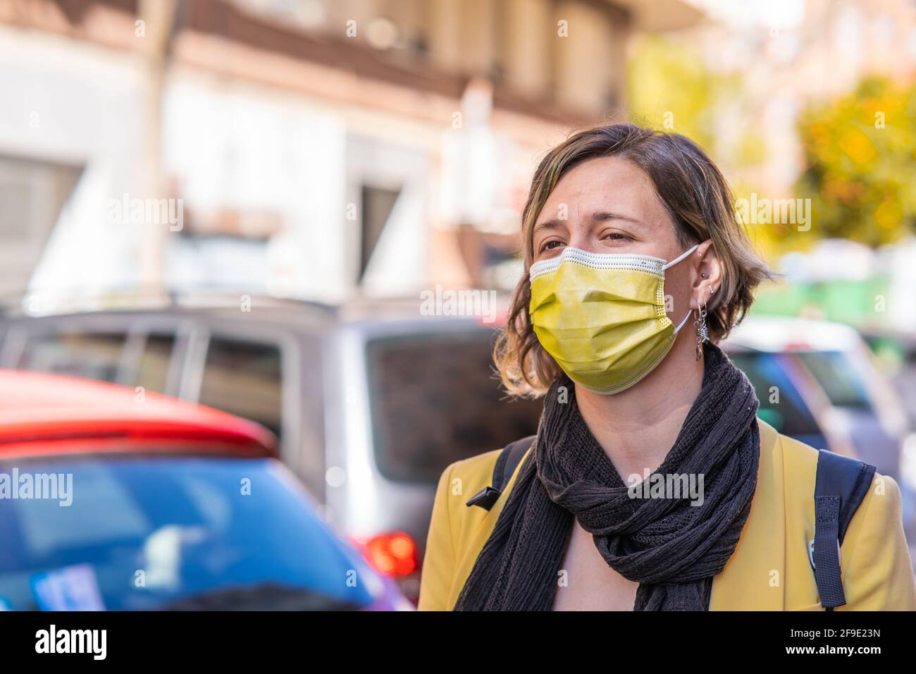 A young Caucasian female wearing a mask walking on the street Stock ...