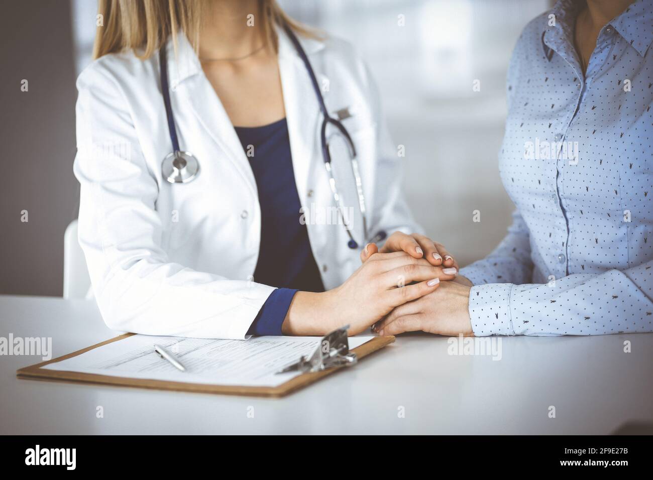Unknown woman-doctor is holding her patient's hands to reassure a ...