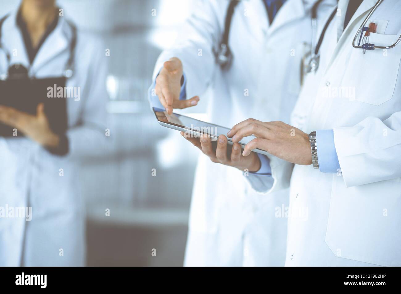 Group of unknown doctors use a computer tablet to check up some medical ...
