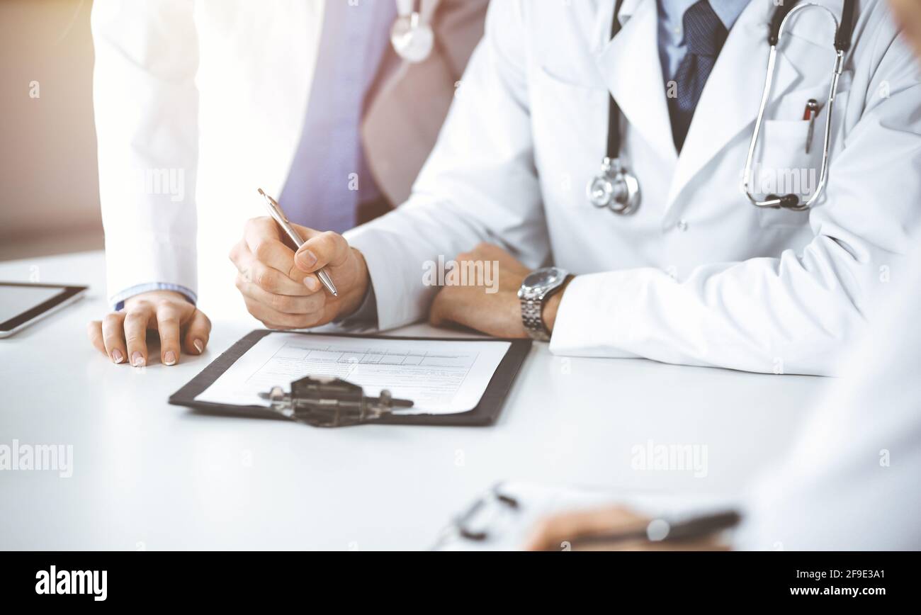 Group of unknown doctors are sitting at the desk and discussing ...