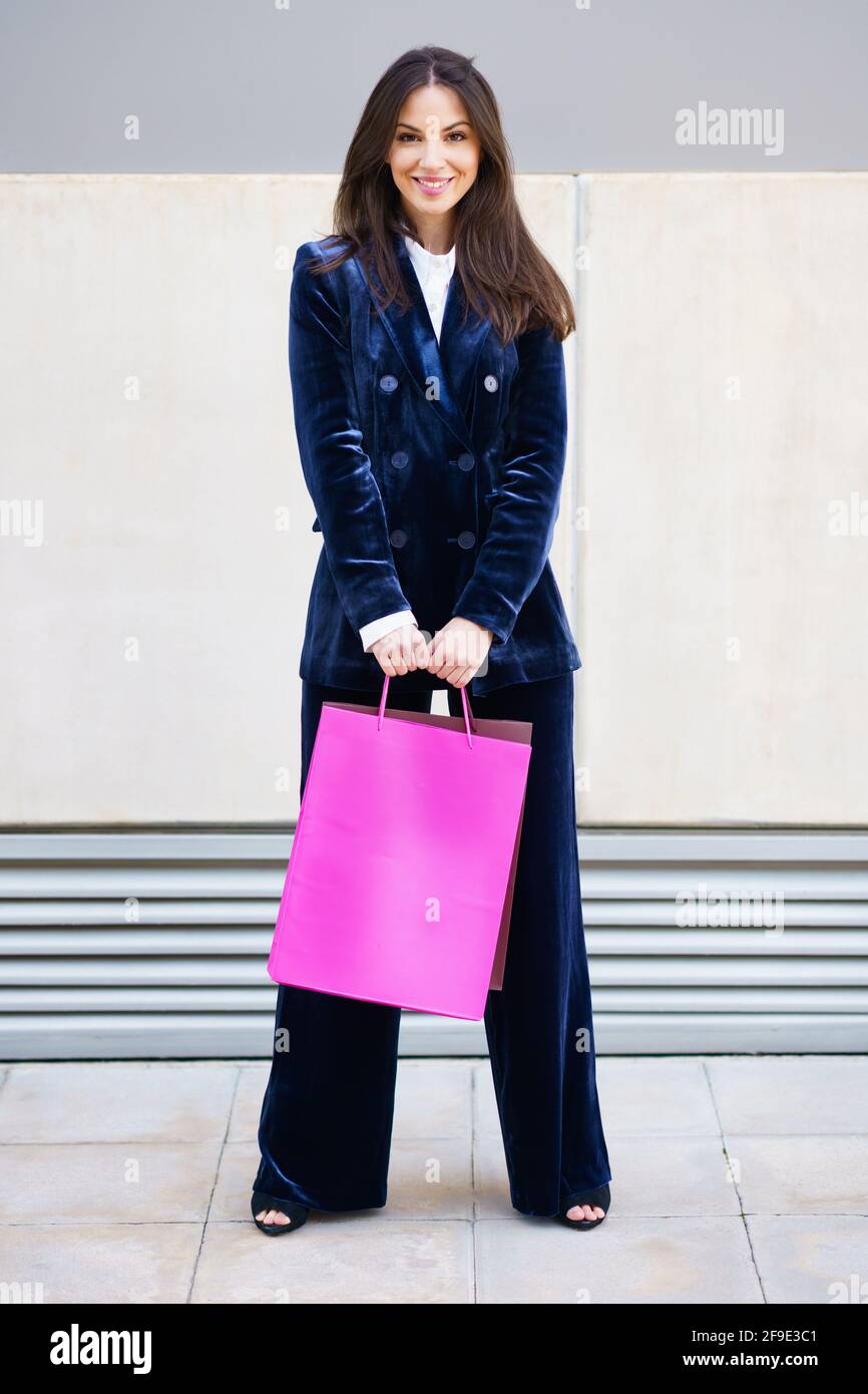 Young woman wearing blue suit carrying several shopping bags near a ...
