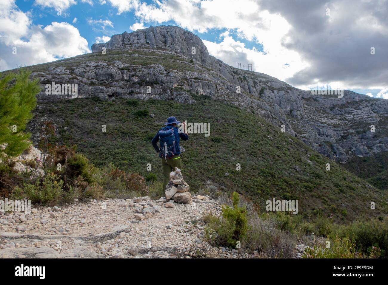 A back view of a hiker admiring the beautify of high rock mountains ...