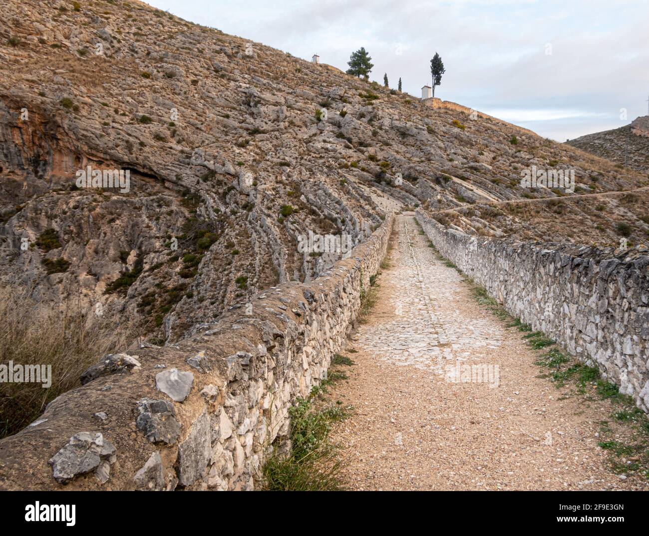 A narrow rural path with a stone fence built on a layered stone ...